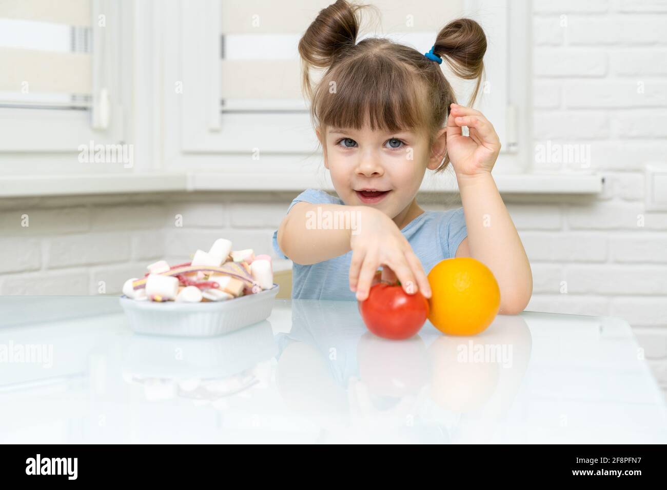 kid girl chooses between sweet candies and vegetables. the child ...
