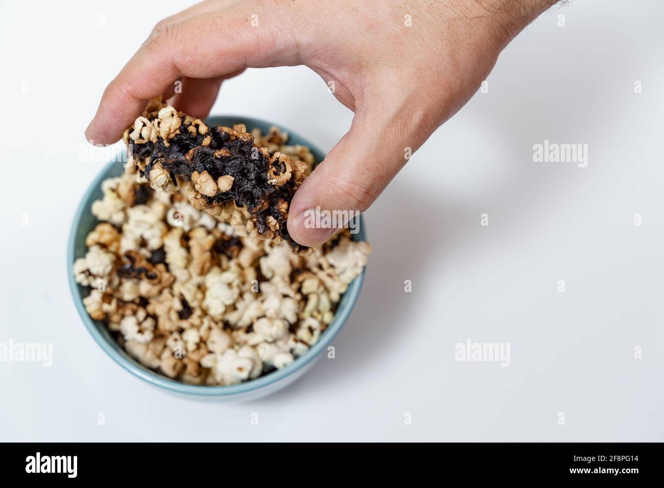 spoiled burnt popcorn in a blue cup. man's hand close up Stock Photo ...