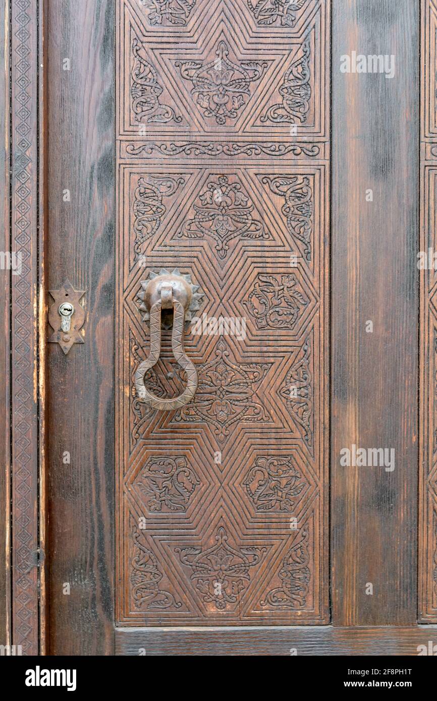 Vertical shot of an old wooden door with engravings of Bardo National ...