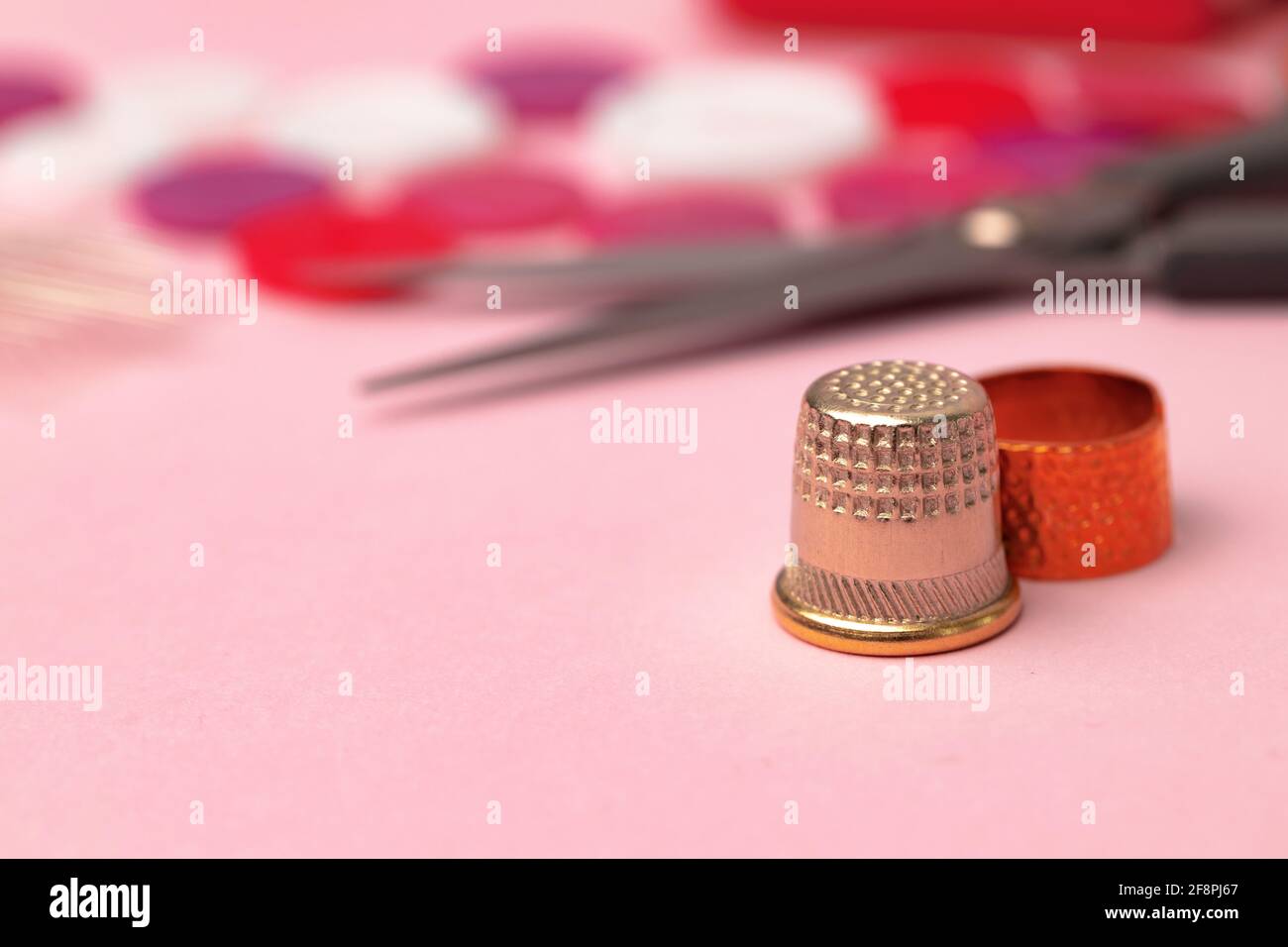 Iron thimbles for sewing on pink background Stock Photo - Alamy
