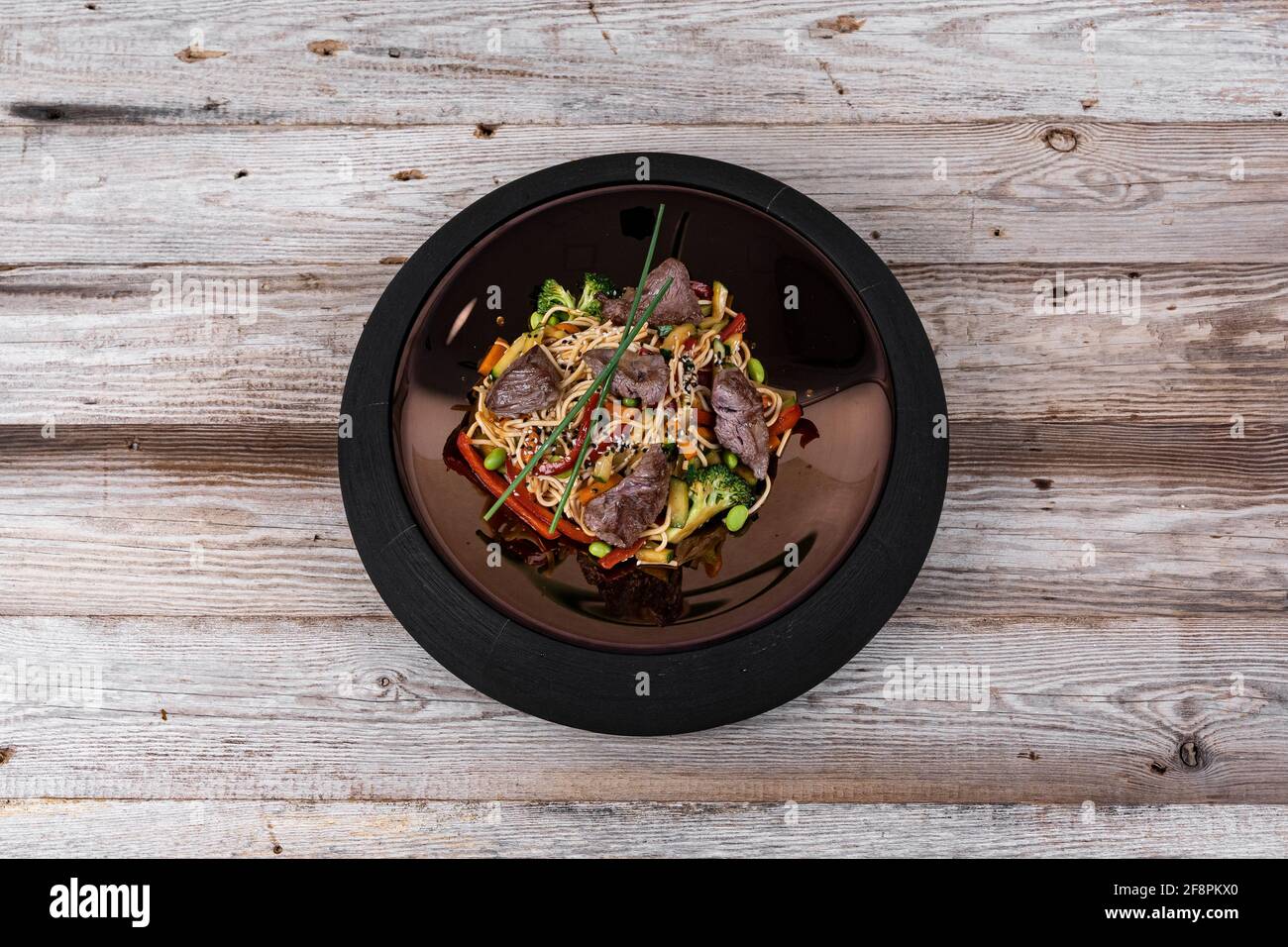 Wok tossed beef noodles on wooden background. Ingredients Beef fillet ...