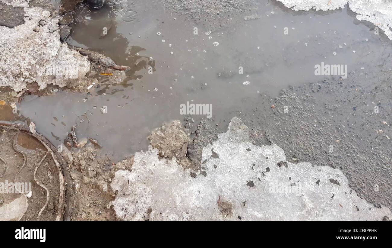 The texture of a muddy puddle with snow, ice and debris, spring ...