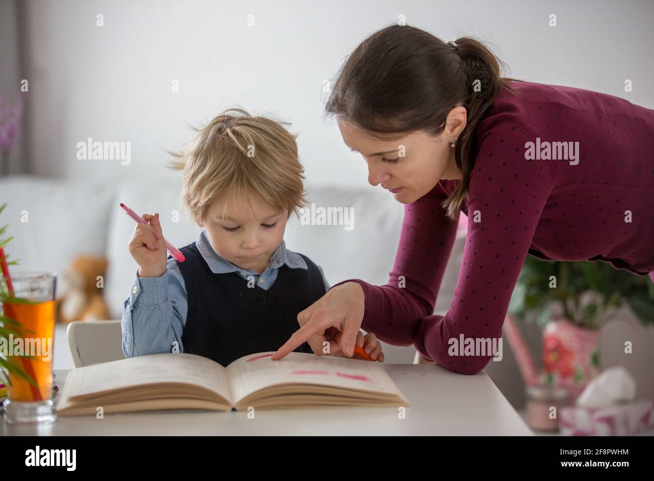 Cute preschool child, blond boy, filling some homework in a work book ...