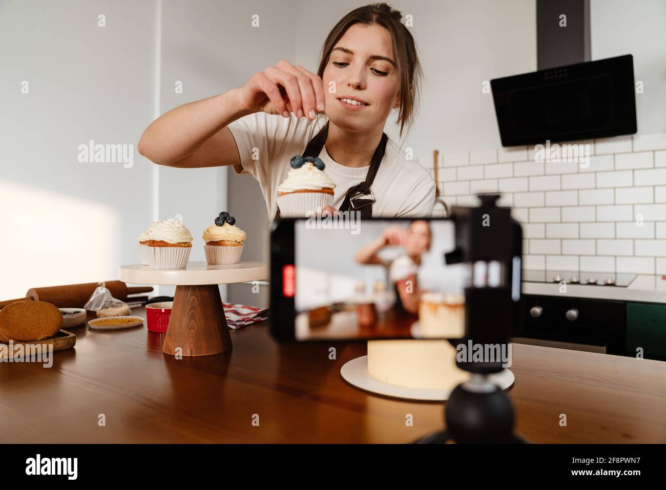 Camera footage of pleased baker woman making cake with cream in kitchen ...