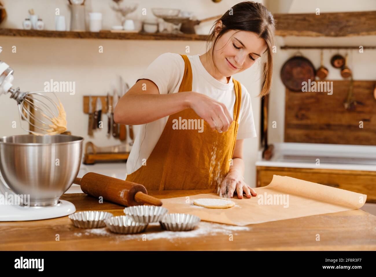 Beautiful happy pastry chef woman smiling while making tarts at cozy ...