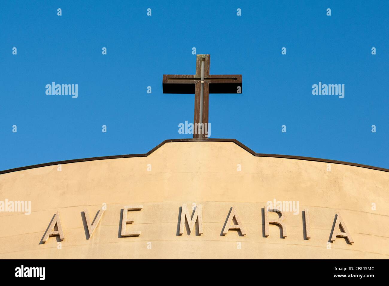 Shot of a Christian cross on the top of church roof, written AVE MARIA ...