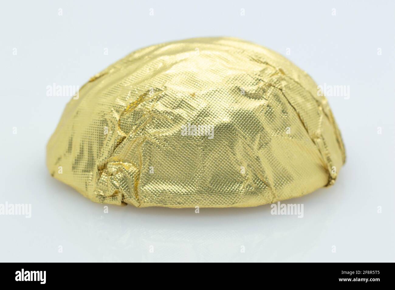 chocolate candy in a gold shiny package on a white background ...