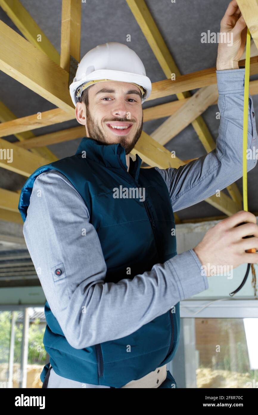 foreman examining framework with measure tape at construction site ...