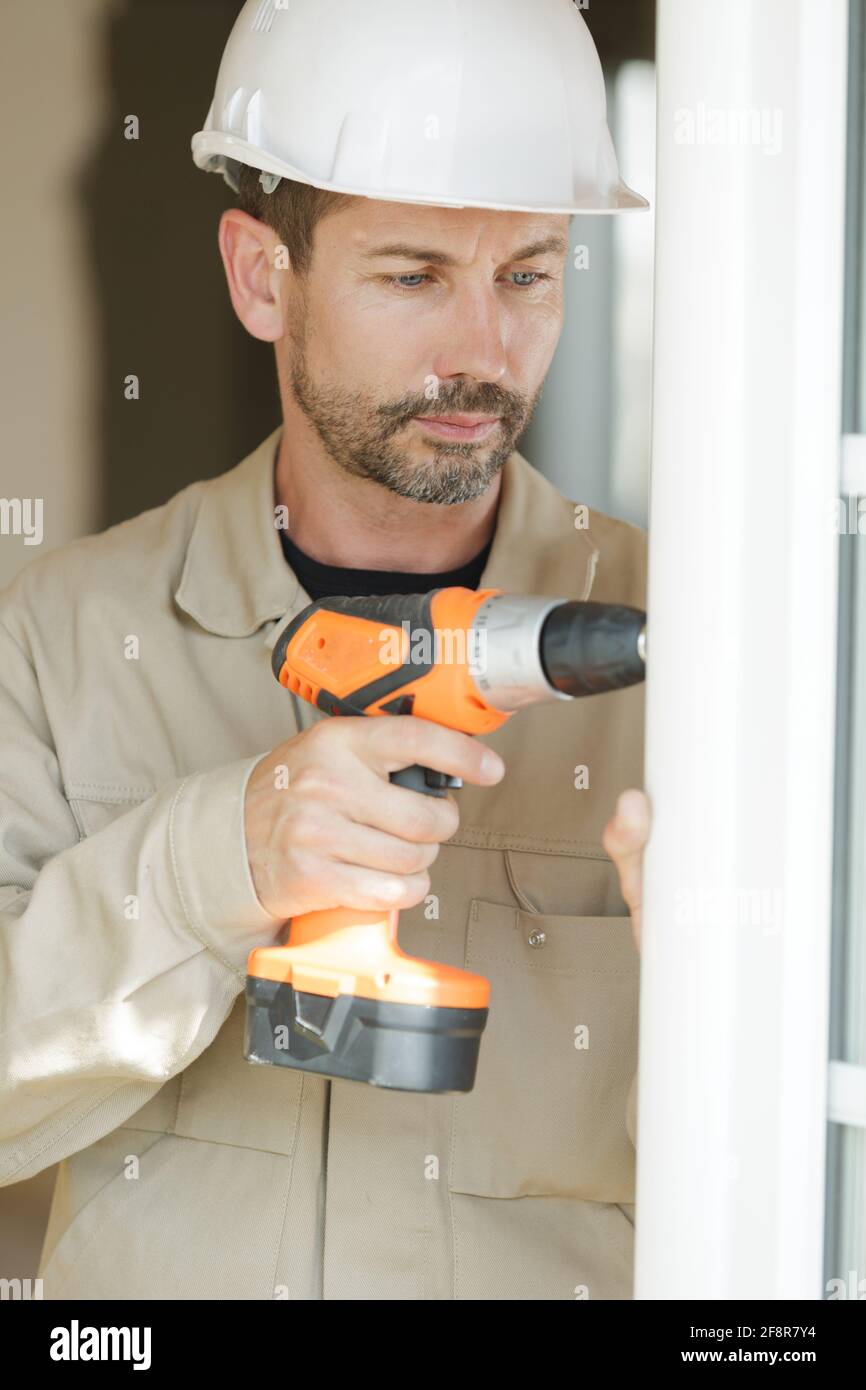 man drilling a hole in a window frame Stock Photo - Alamy