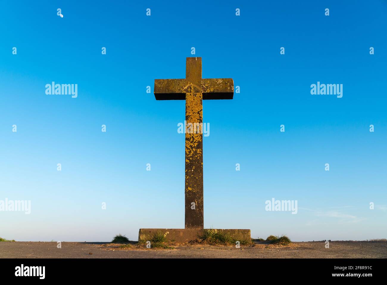 Big old Christian stone cross covered with bright yellow lichen in ...