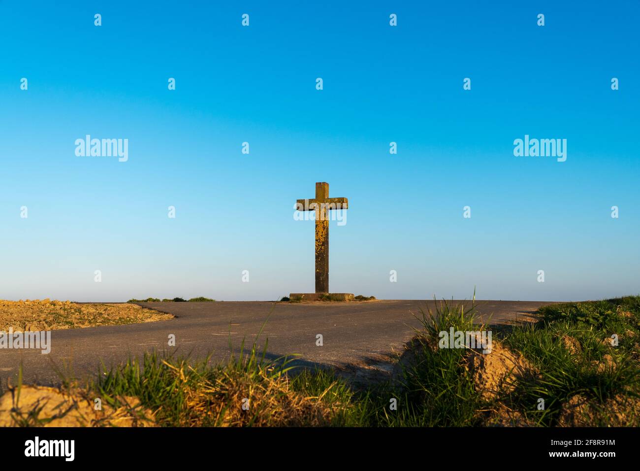 Two rural roads intersect at a big old Christian stone cross in front ...