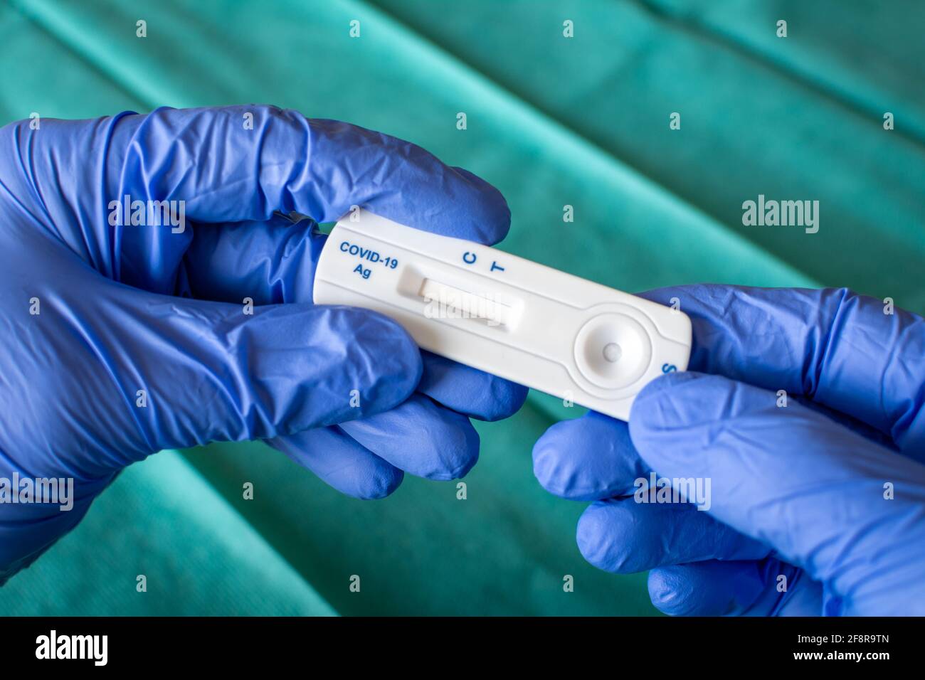 Health care worker with blue surgical gloves holding a COVID-19 Antigen ...