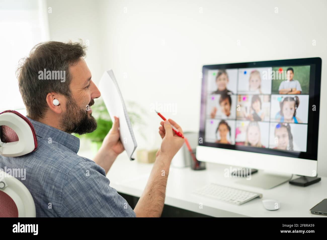 Male teacher having online conference with school children working at ...