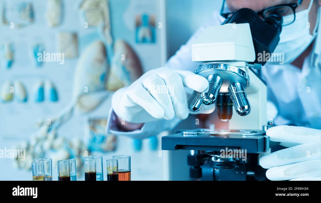 Doctor looking in microscope while working on medical research in ...