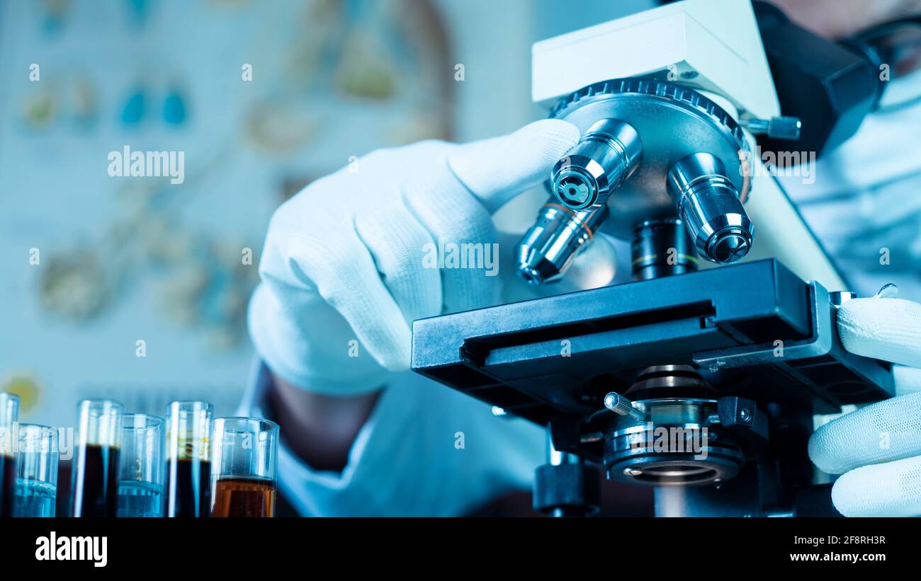 Doctor looking in microscope while working on medical research in ...