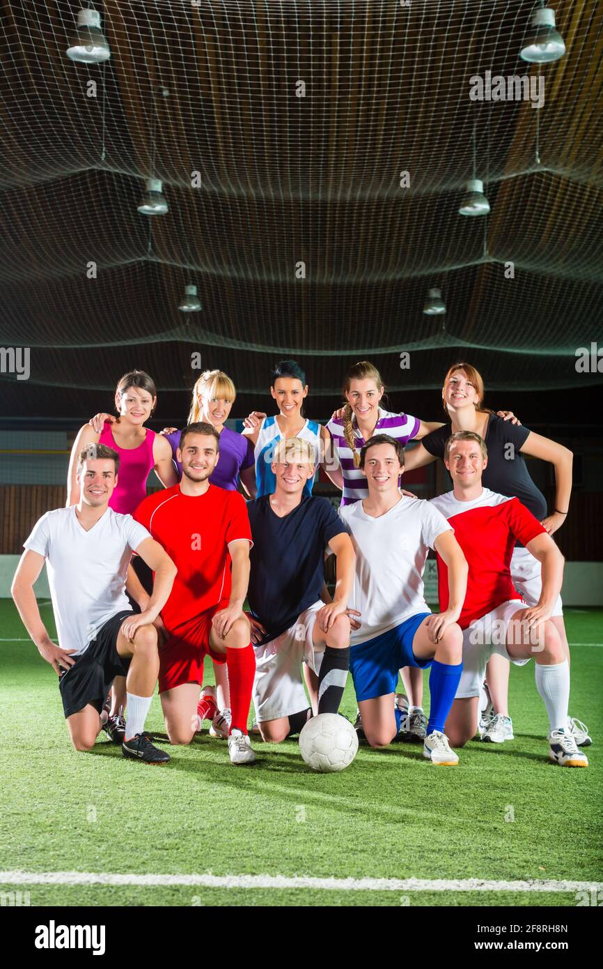 Men and women in mixed sport team playing football or soccer indoor ...