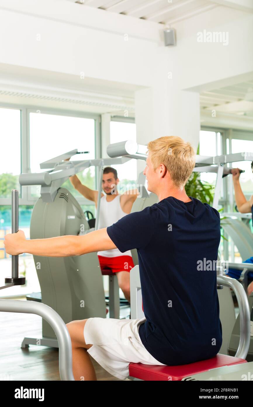 Group of men train on machine in a fitness club or gym Stock Photo - Alamy