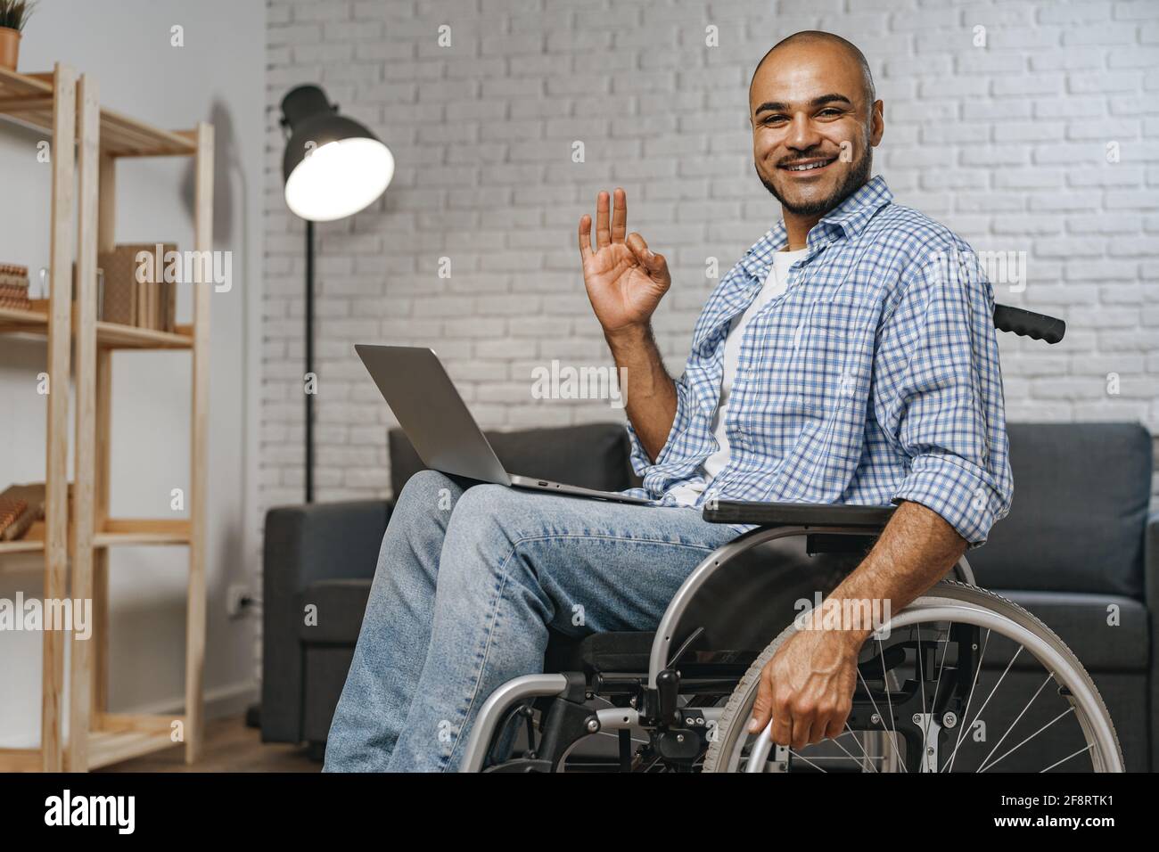 Disabled man sitting in a wheelchair and using laptop Stock Photo - Alamy
