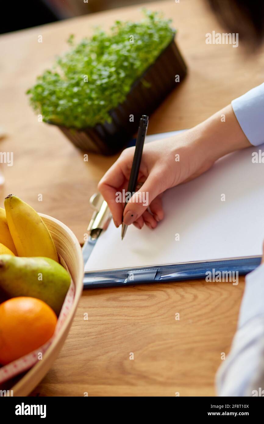 Nutritionist, dietitian woman writing a diet plan, with healthy ...