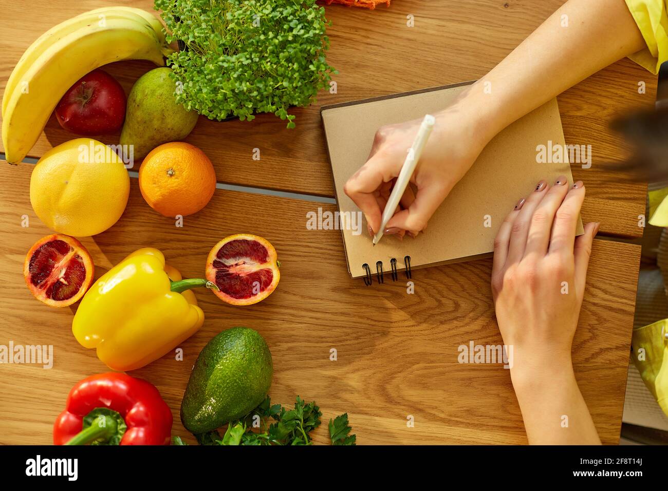 Woman planning, writing weekly meals on a meal planner note or diet ...