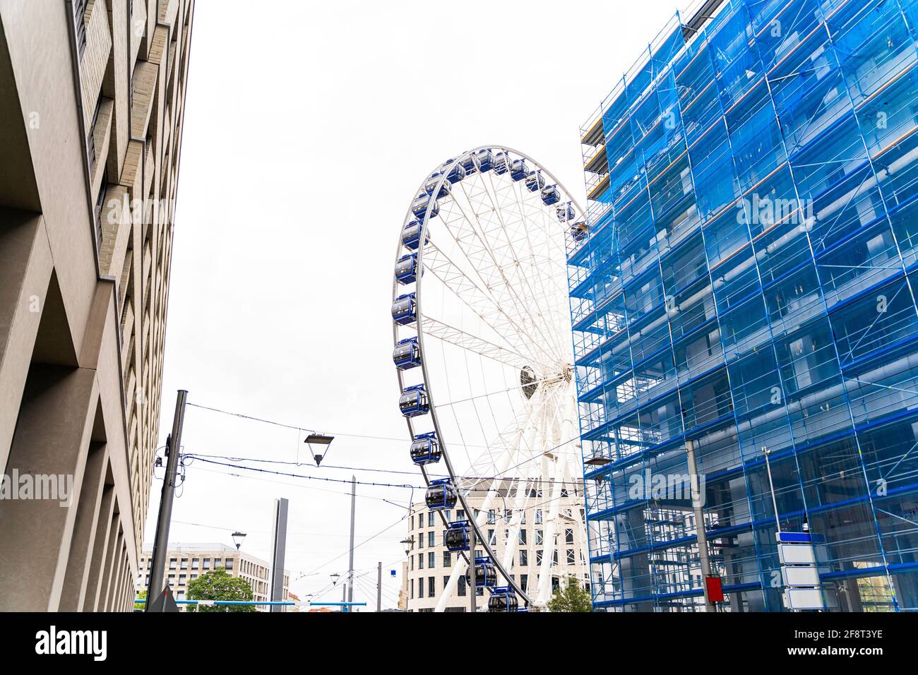 Modern spinning ferris wheel stands next to a building construction ...