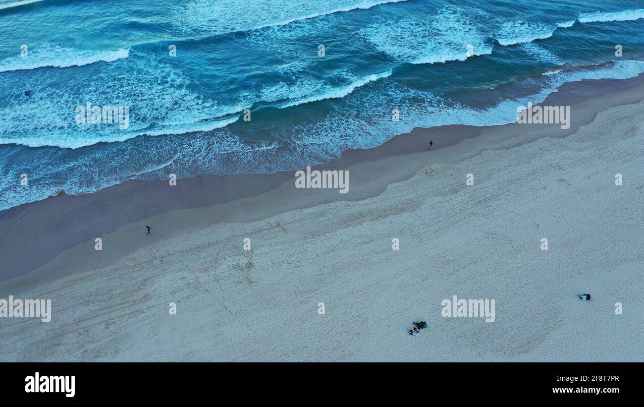 Aerial view of the wavy ocean hitting the sandy beach on the coast ...