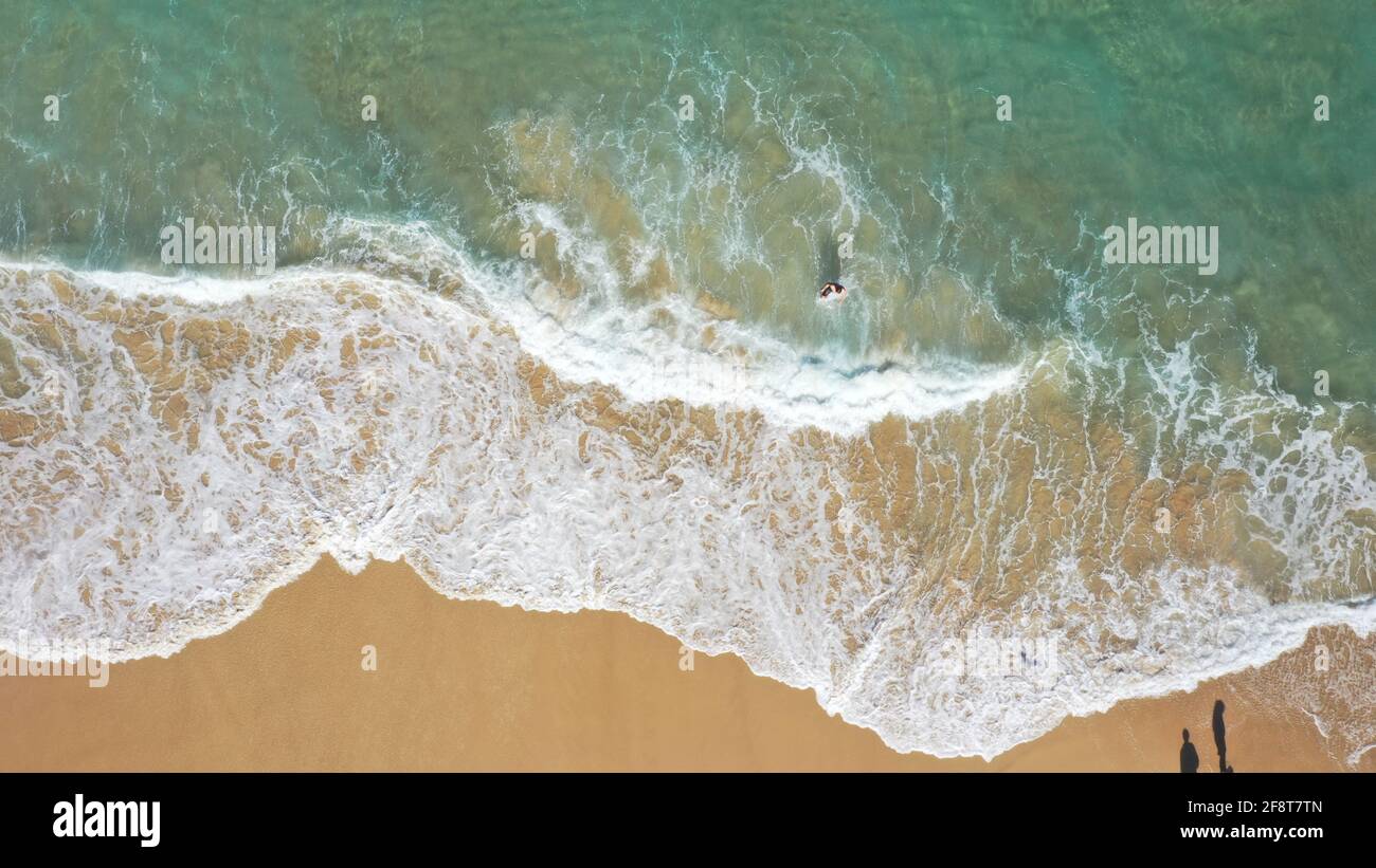 Aerial view of the wavy ocean hitting the sandy beach on the coast ...