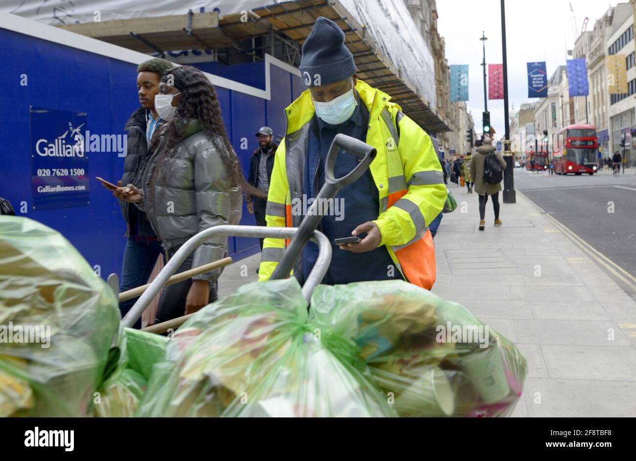 London, England, UK. Street sweeper in Oxford Street looking at his ...
