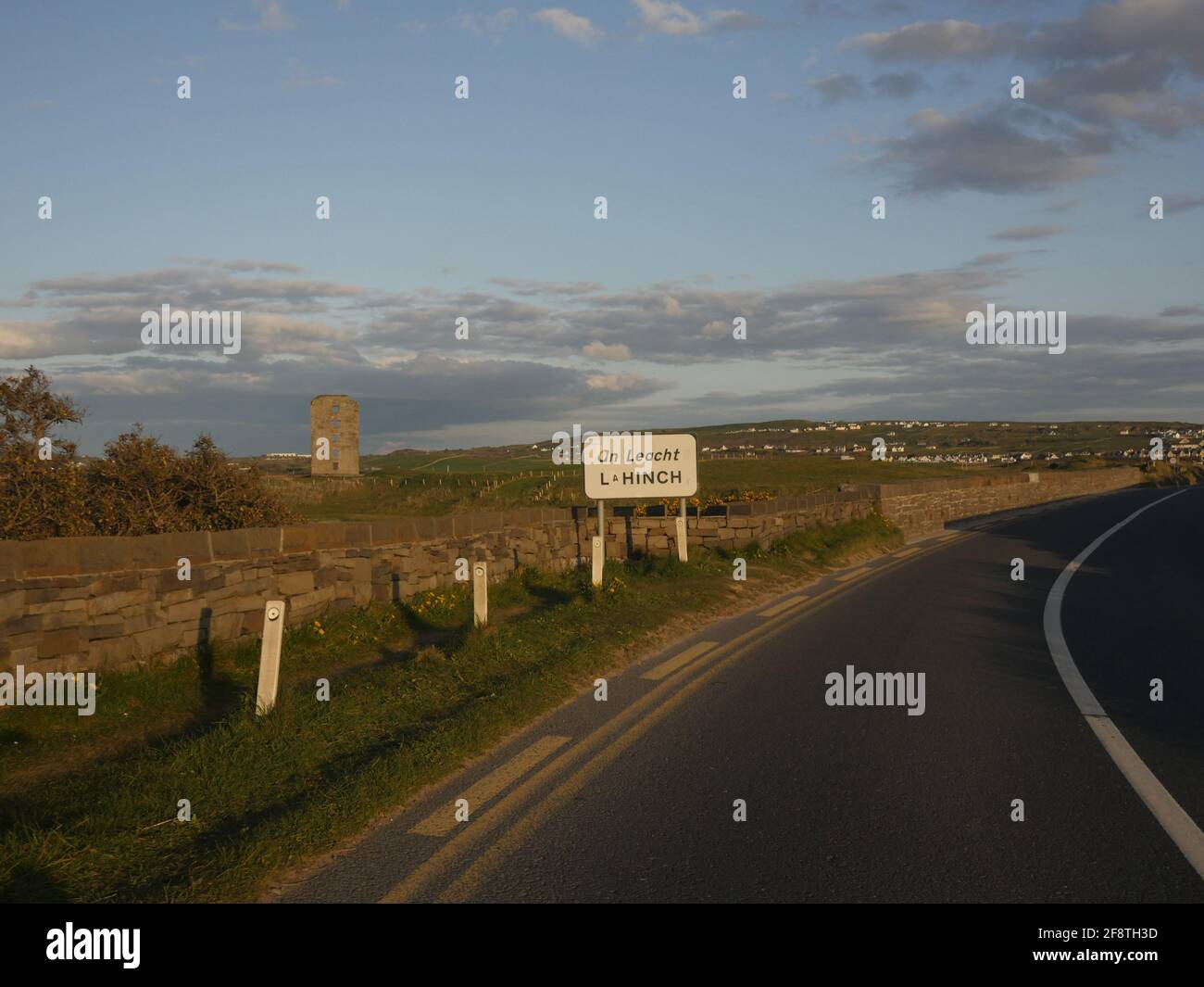 The empty road leading into Lahinch in county Clare Ireland. A signpost ...