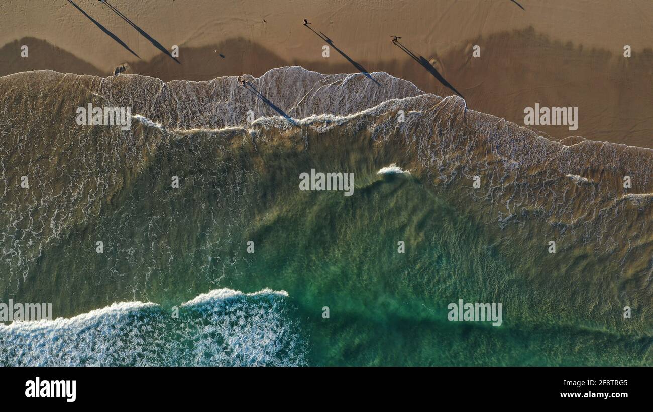 Aerial view of the wavy ocean hitting the sandy beach on the coast ...