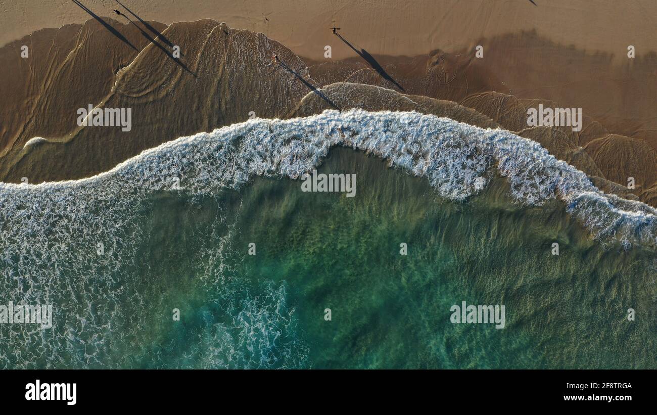 Aerial view of the wavy ocean hitting the sandy beach on the coast ...