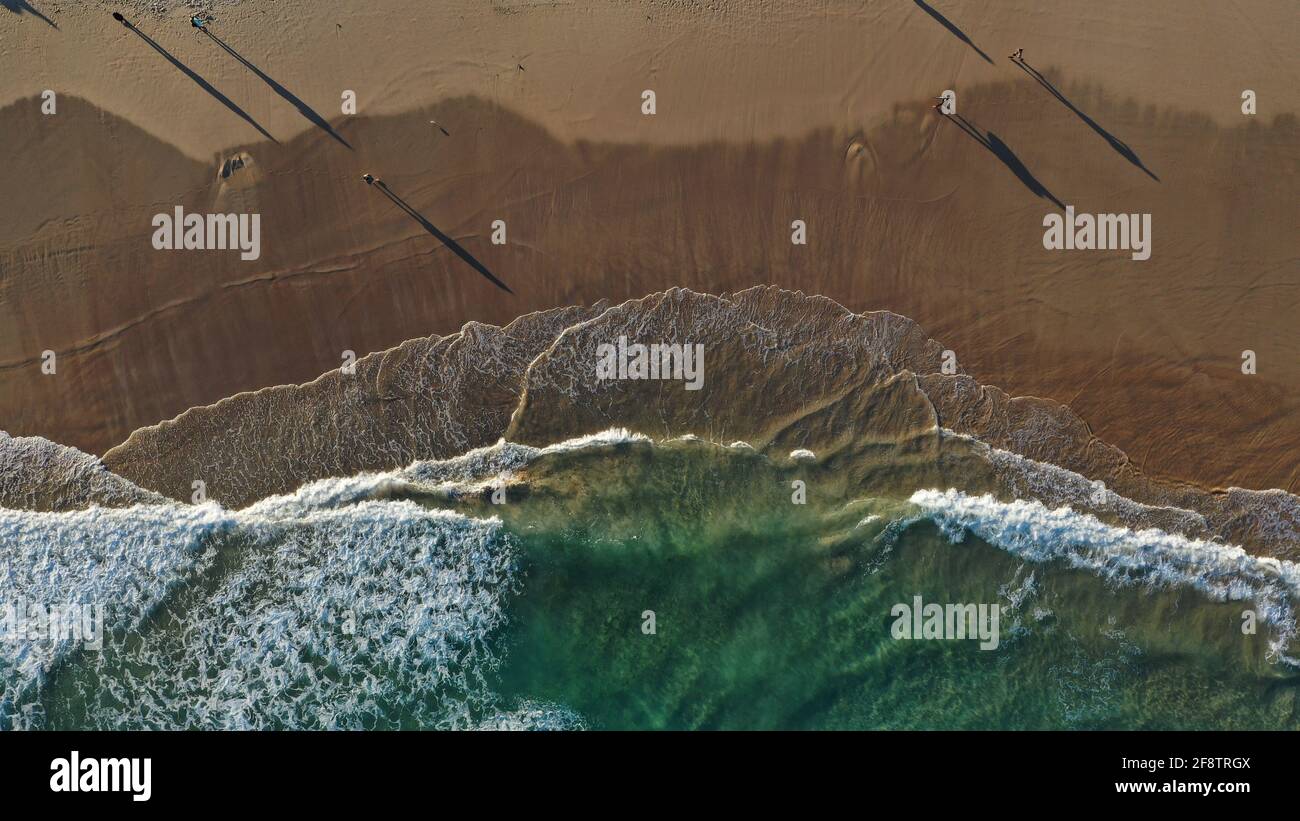 Aerial view of the wavy ocean hitting the sandy beach on the coast ...