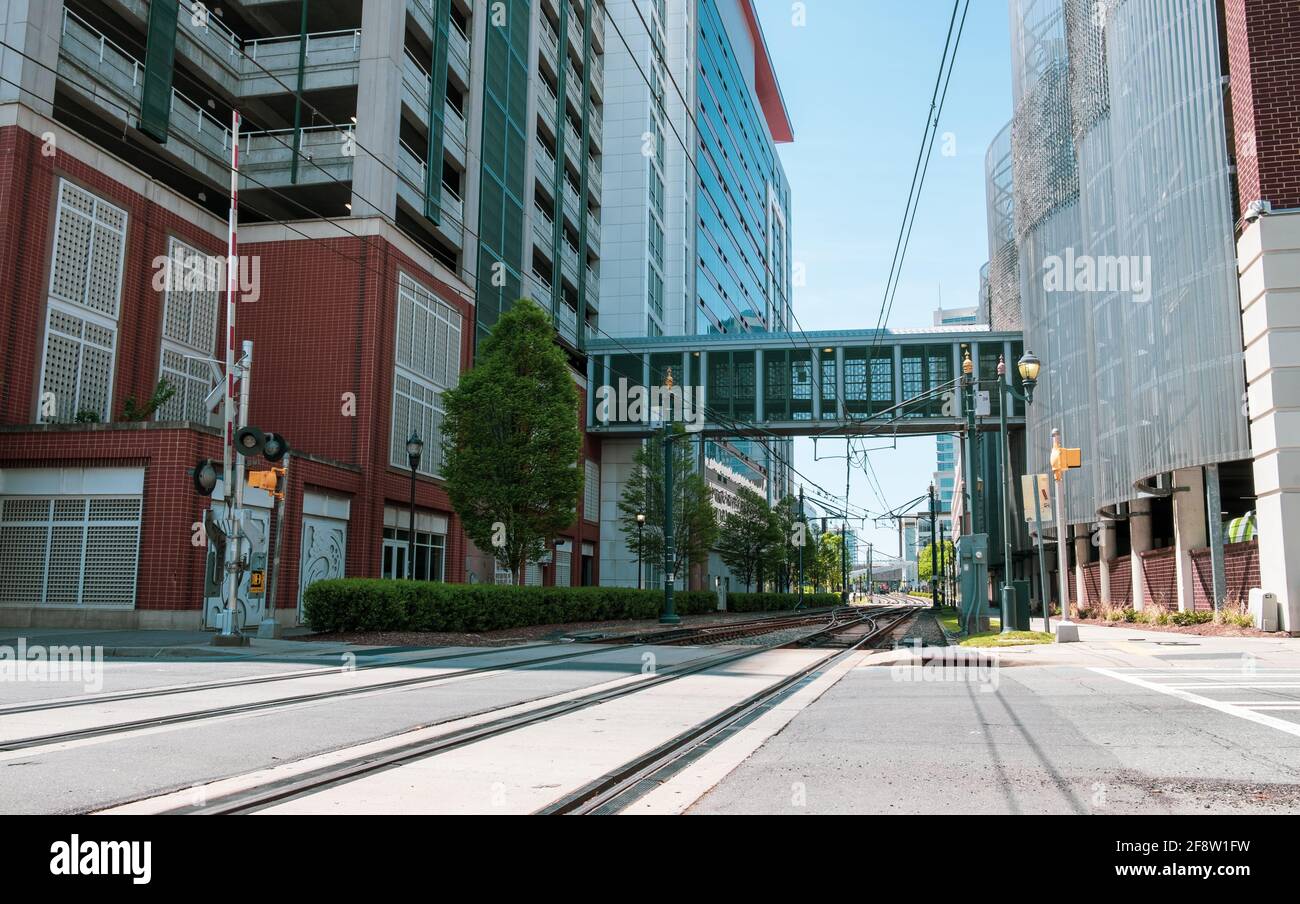 Low angle view of light rail tracks running under elevated walkway between two buildings in ...