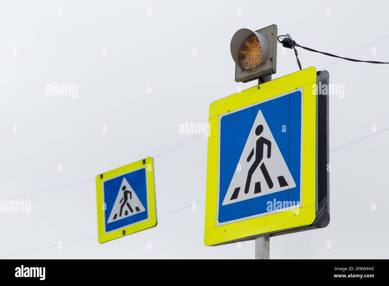 Road sign white triangle with a man in a blue square means a pedestrian crossing. The yellow ...