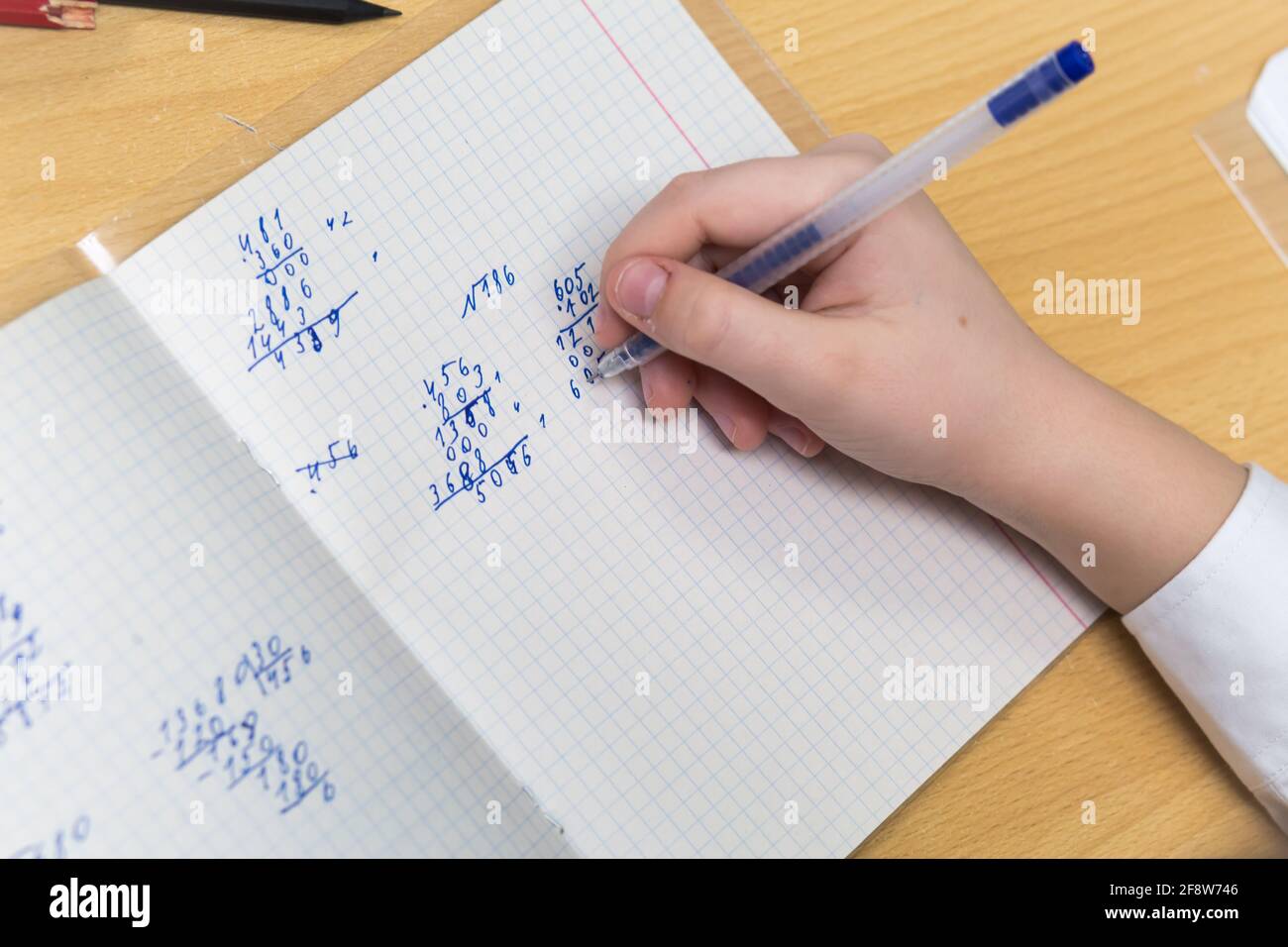 The girls hand with a fountain pen with blue ink solves examples in ...