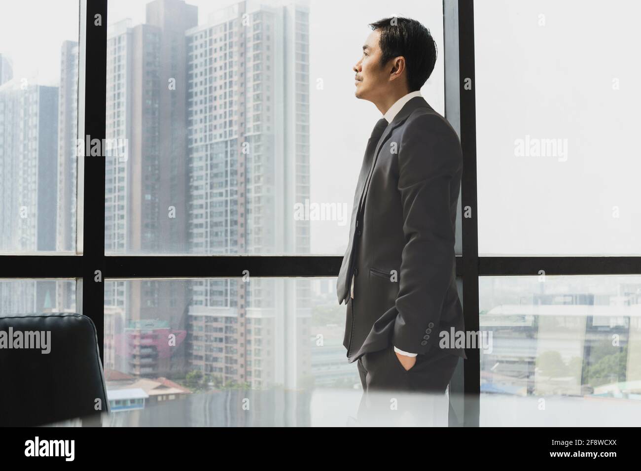 Businessman standing window looking distance hi-res stock photography ...