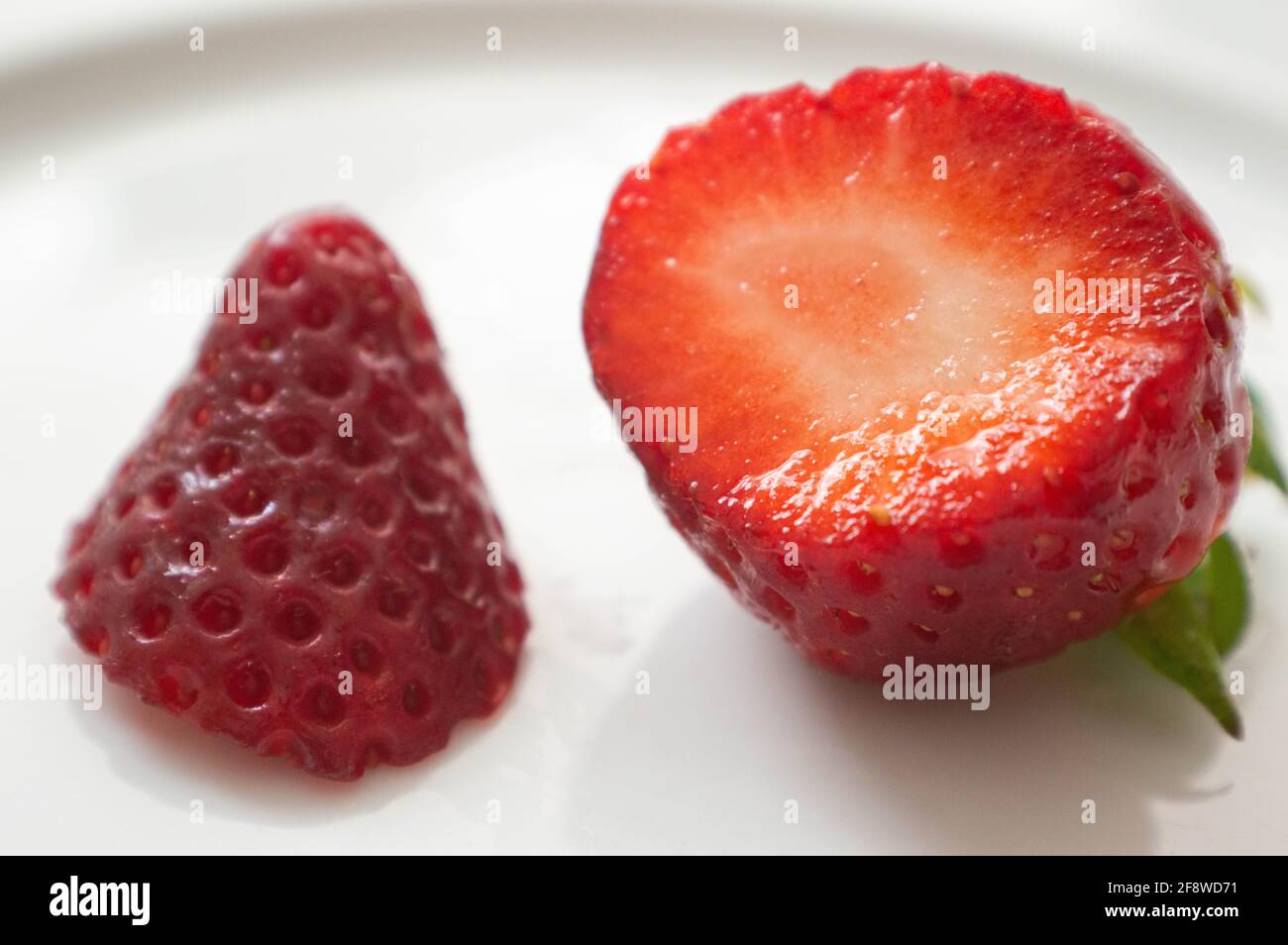 Strawberries cut on a white plate. Isolated Stock Photo - Alamy