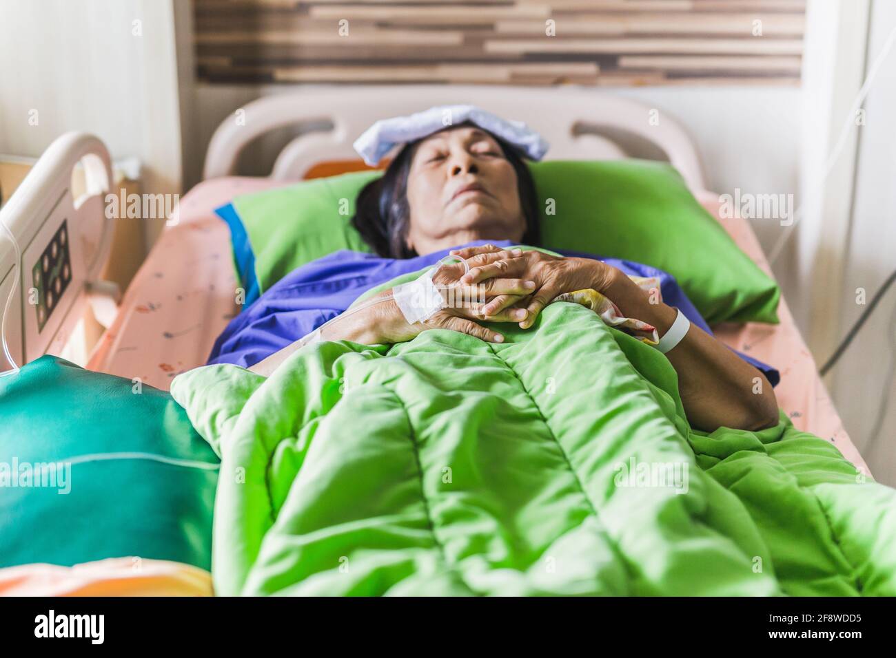 Senior patient hand with injection saline lying in the hospital bed ...