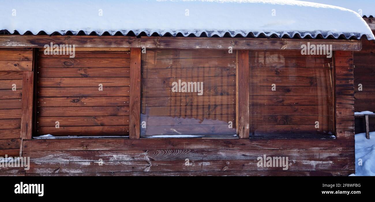 A snow-covered roof of a wooden house. Wooden block building with lots ...