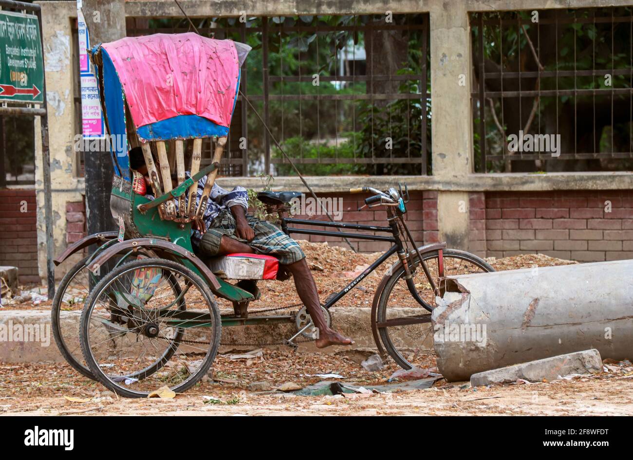 a rickshaw puller get tried and slept on his rickshaw in a lazy after ...