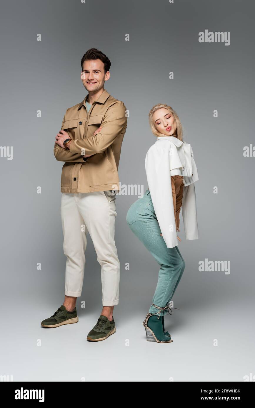 full length of happy models in pants and jackets posing and smiling on ...