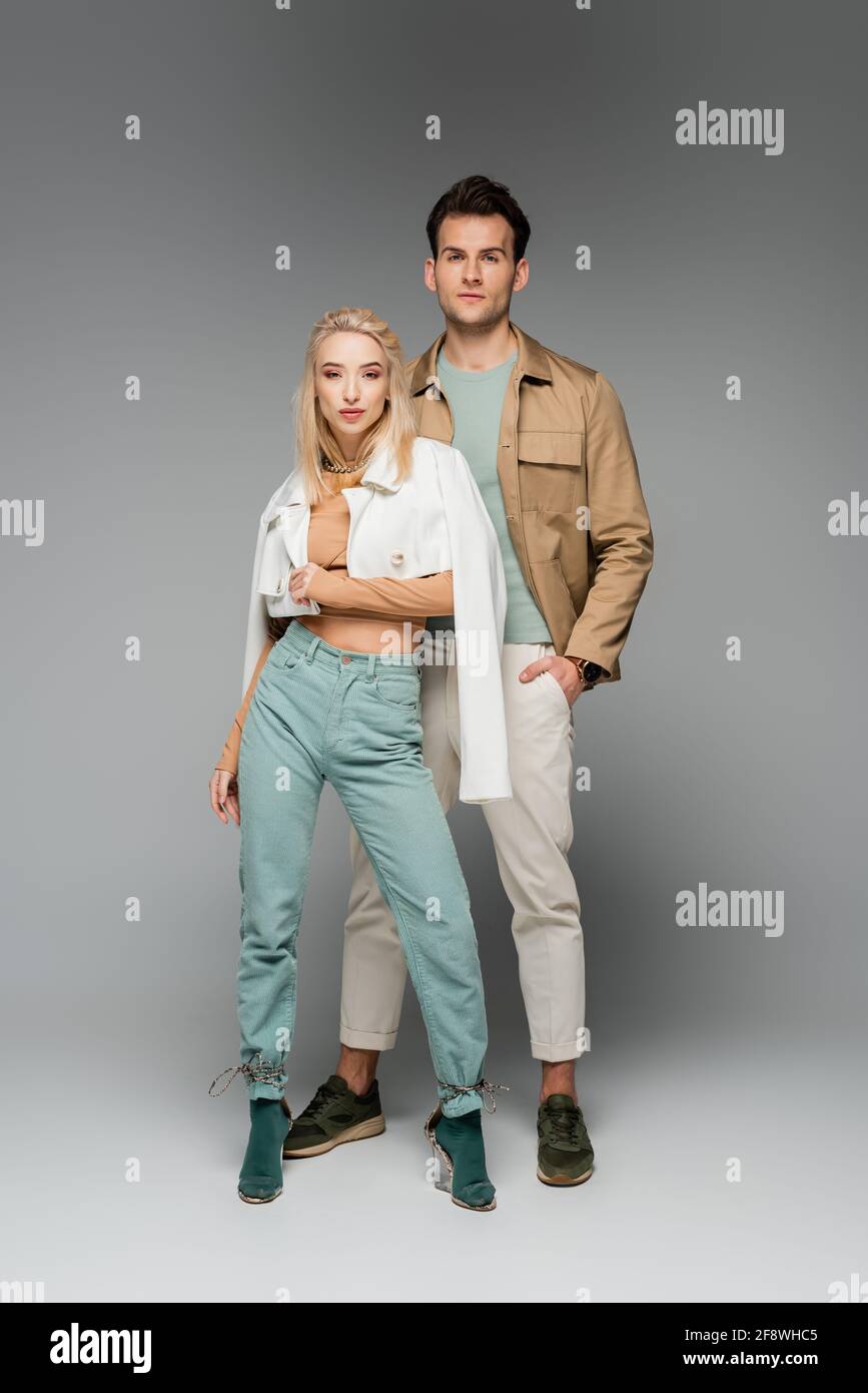 full length of stylish model in pants and jacket posing with woman on ...