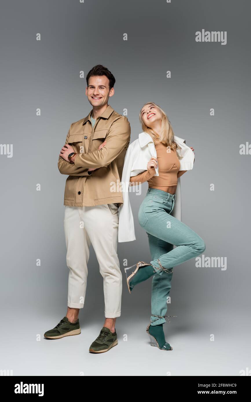 full length of trendy models in pants and jackets posing and smiling on ...