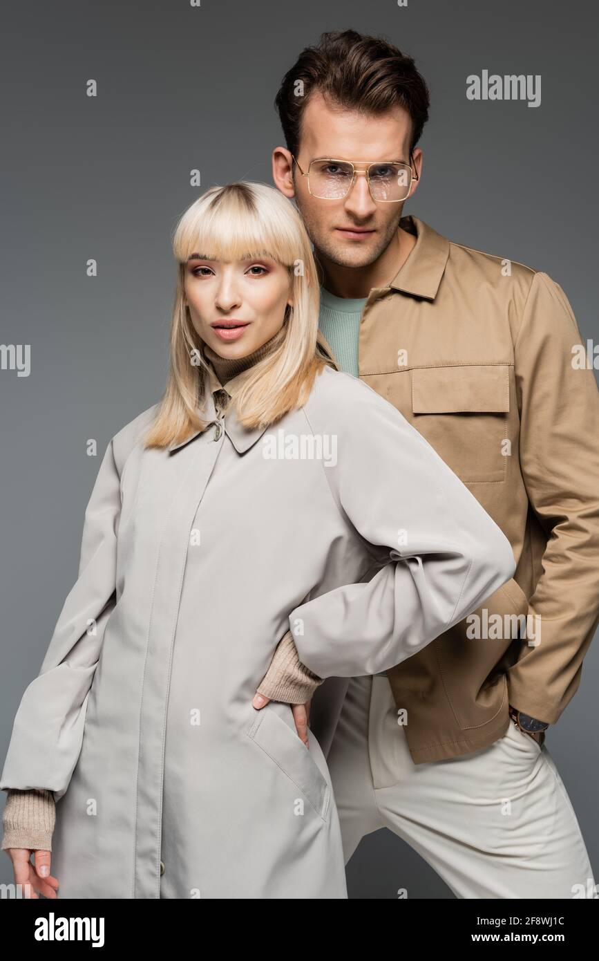 young trendy models posing while standing together isolated on grey ...