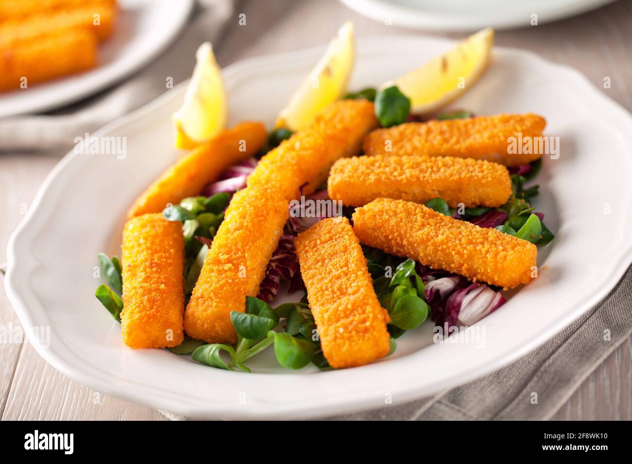 Fresh breaded fish fingers served with mixed salad Stock Photo - Alamy