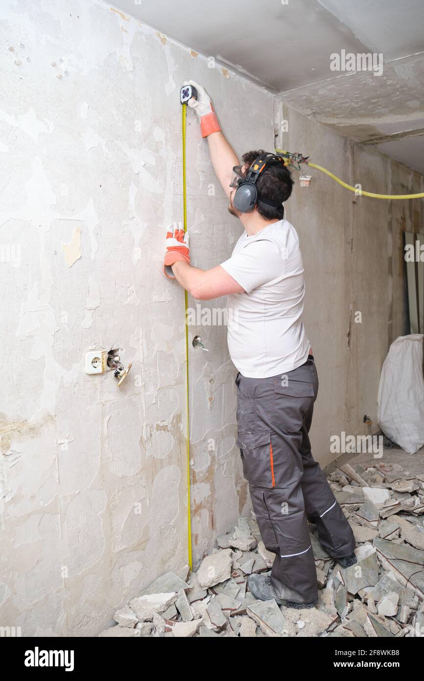 Builder man using a measuring tape at the construction site ...