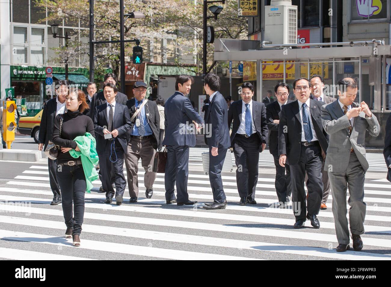 Japanese male office workers wearing business suits walking across ...