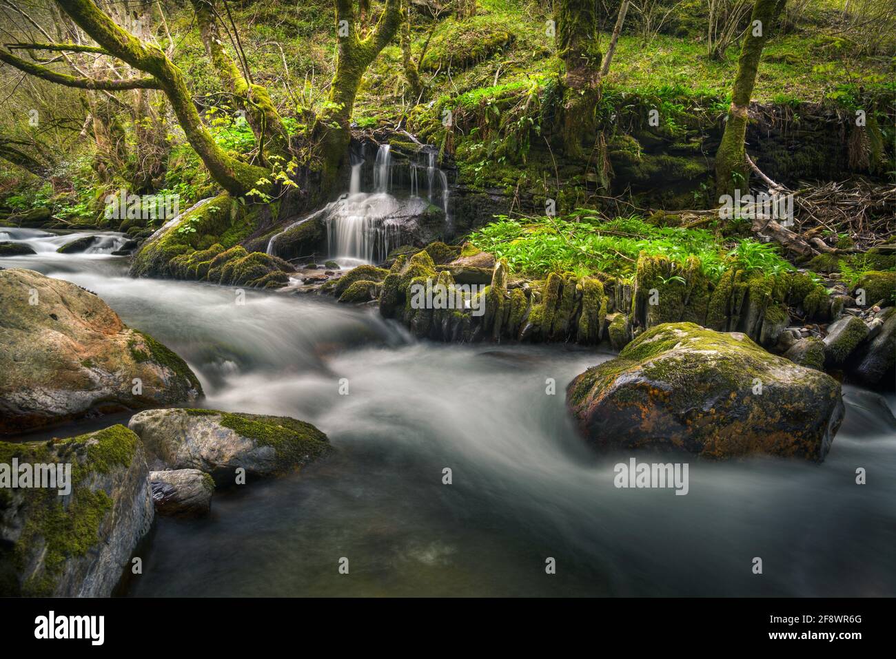Confluence of a small stream and a river channeled with old slab walls ...