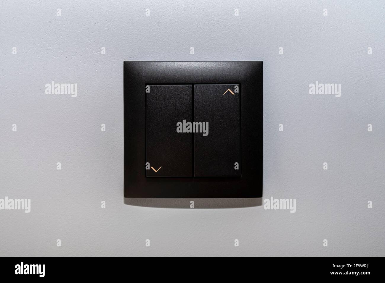 Black frame and button of the roller shutter switch up and down on gray ...