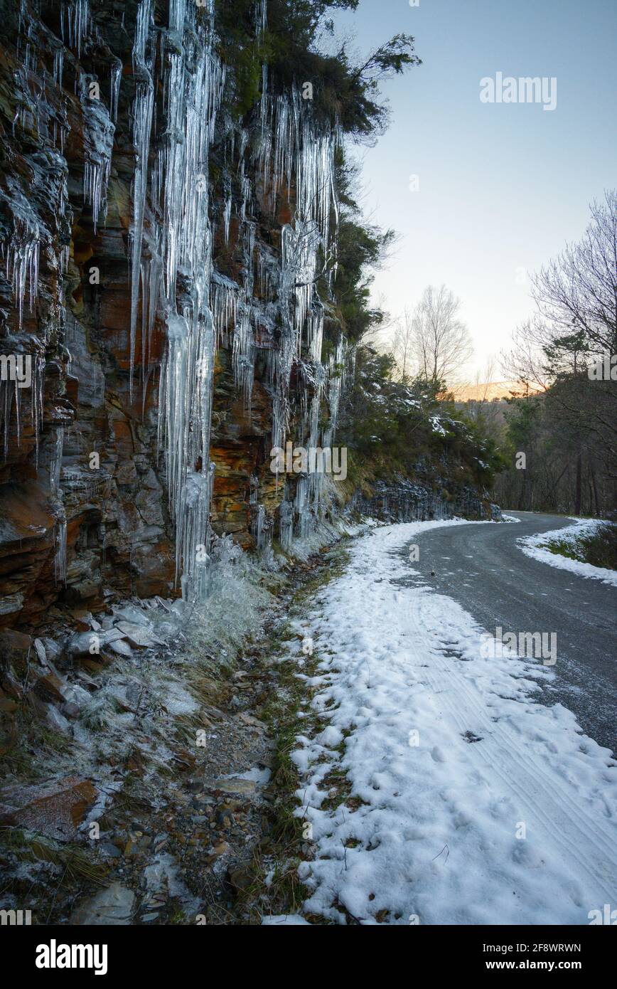 Ice covered mountain road along a cliff with abundant icicles after a ...
